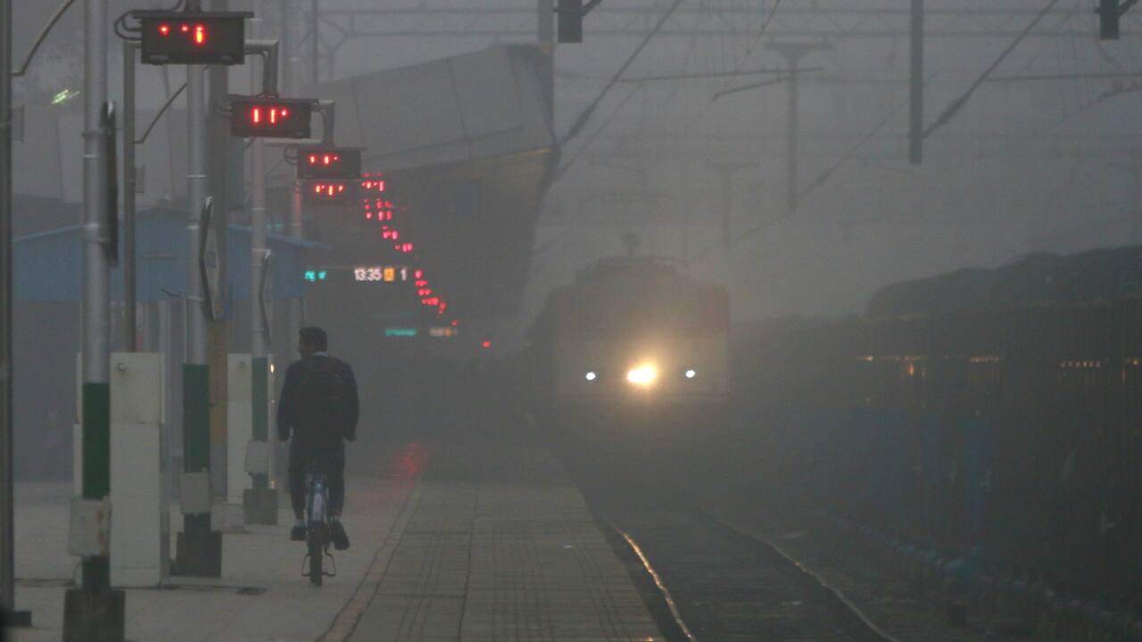 A man in a wheelchair crosses railway tracks on a cold and foggy ...